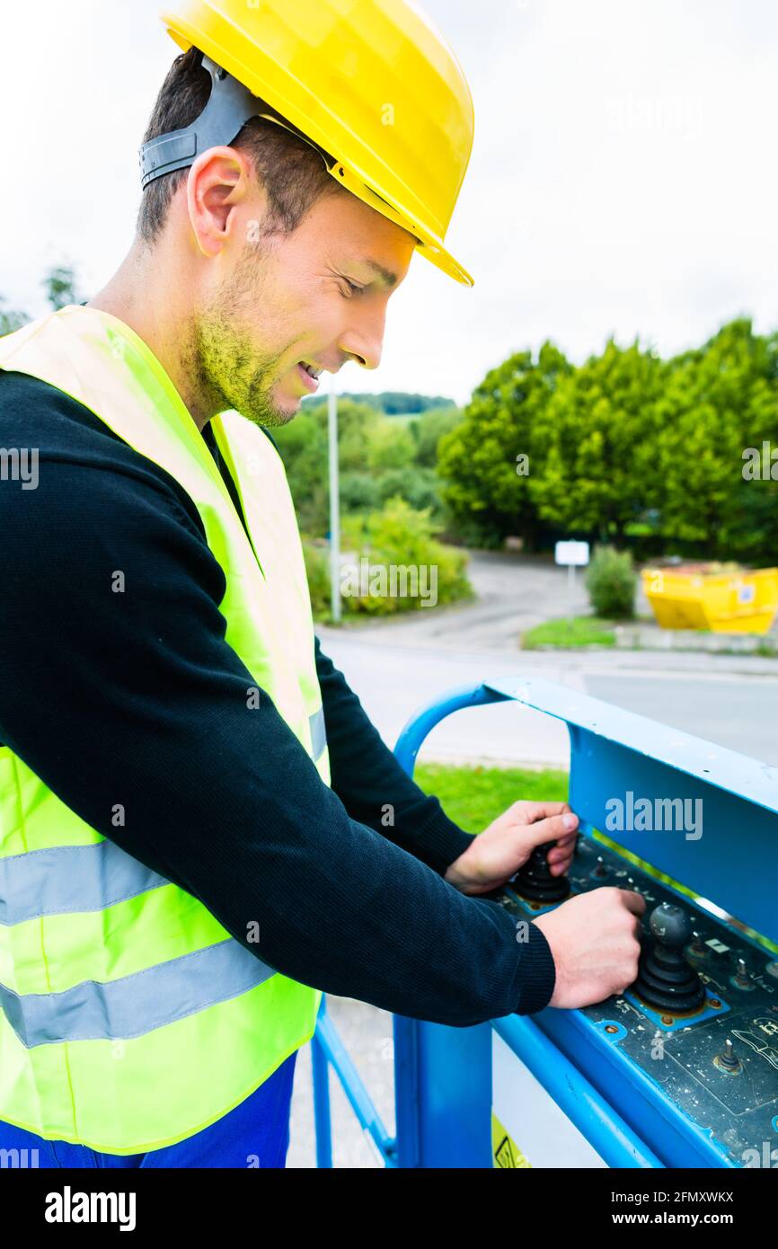 Construction workers or crane driver on site driving hydraulic lifting ...