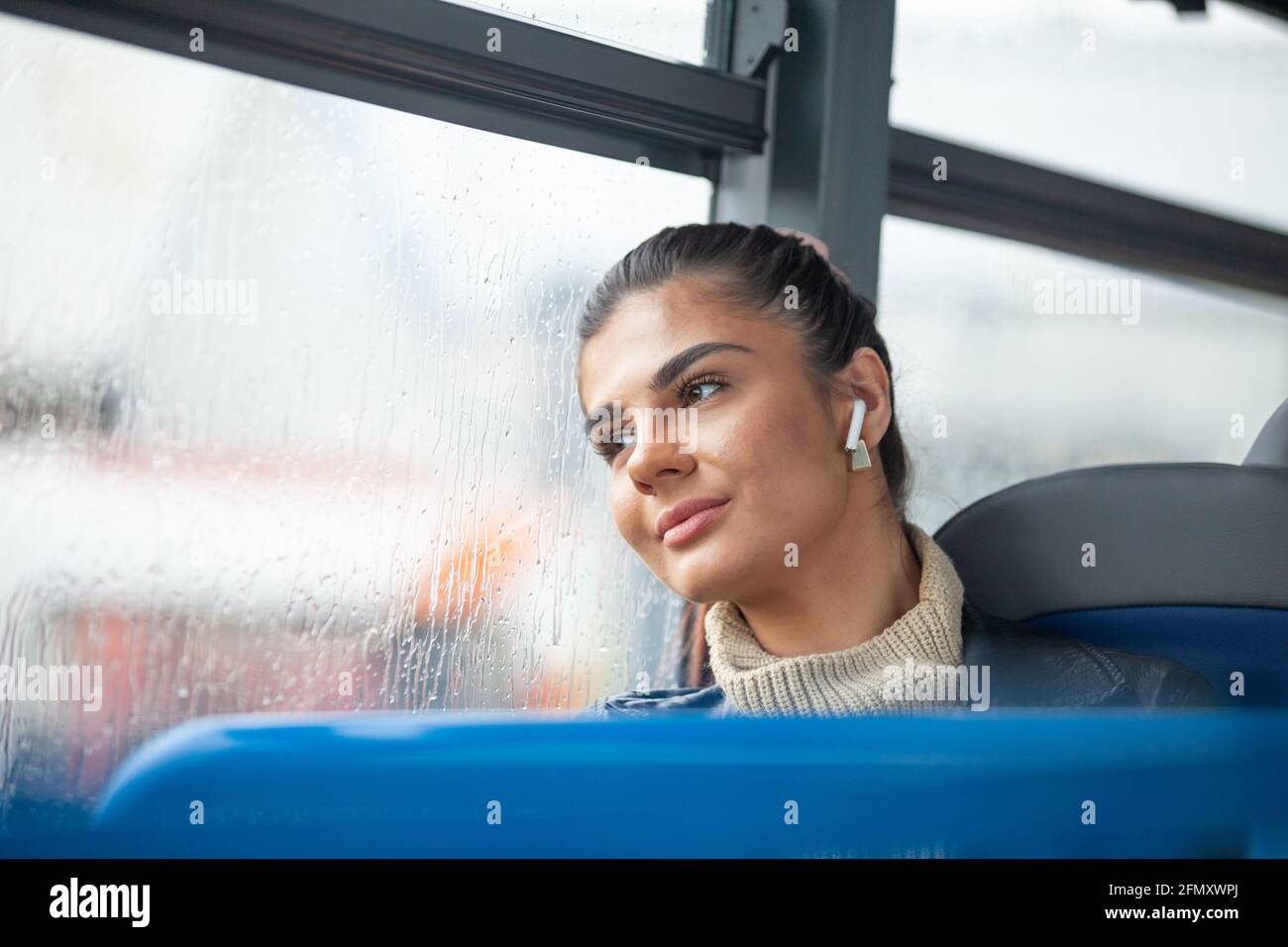 woman looking out of window of a bus whilst listening to music Stock ...