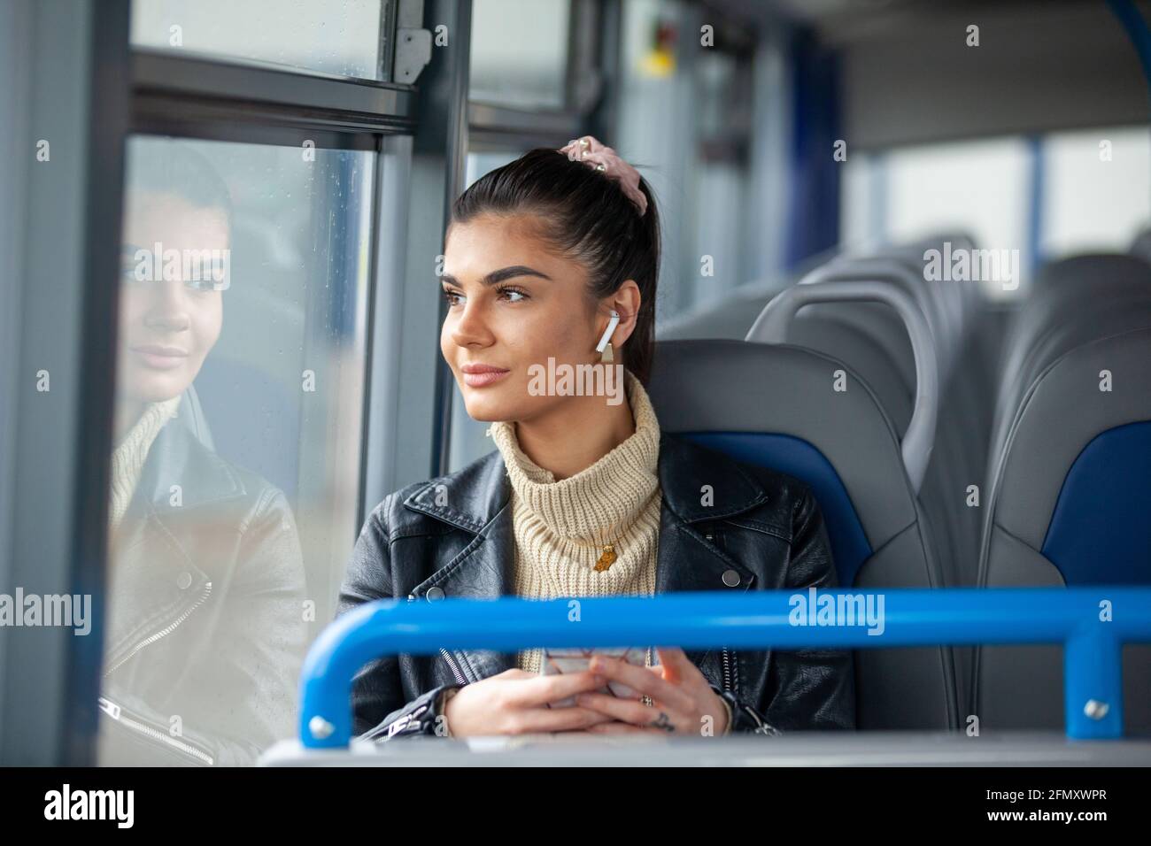 woman looking out of window of a bus whilst listening to music Stock ...