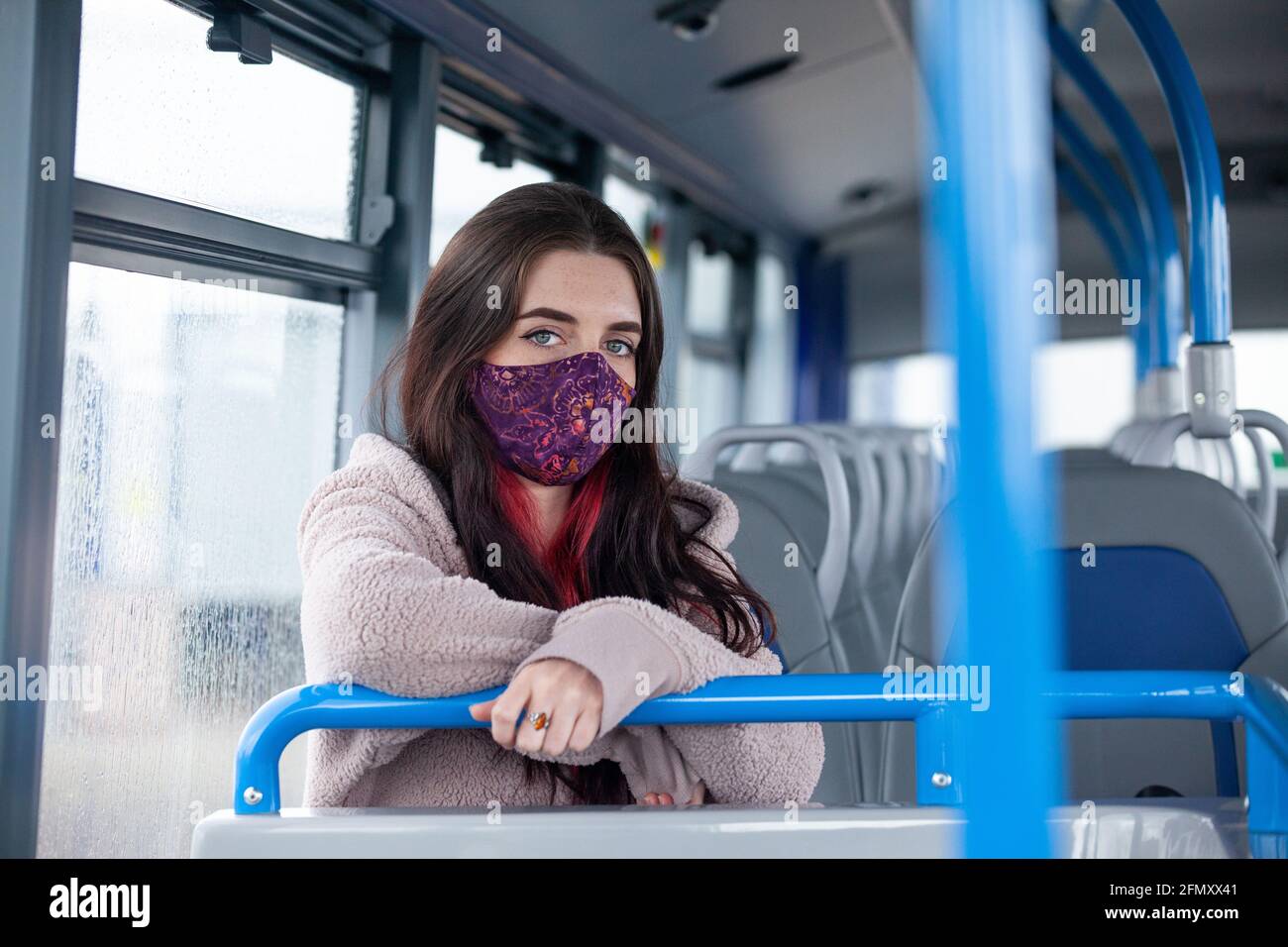 A young female student on a bus with her arms on a rail Stock Photo - Alamy