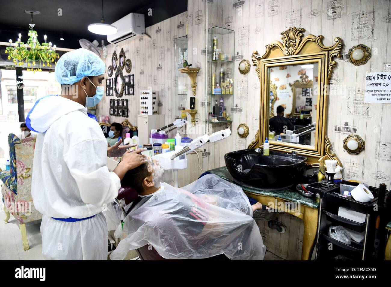 A salon staff wearing personal protective equipment (PPE) as a ...