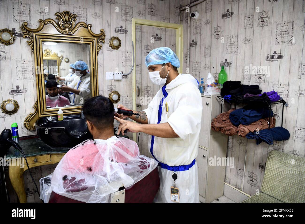 A salon staff wearing personal protective equipment (PPE) as a ...