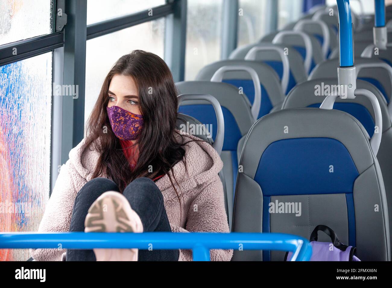 a woman sitting on a bus looking out the window Stock Photo - Alamy