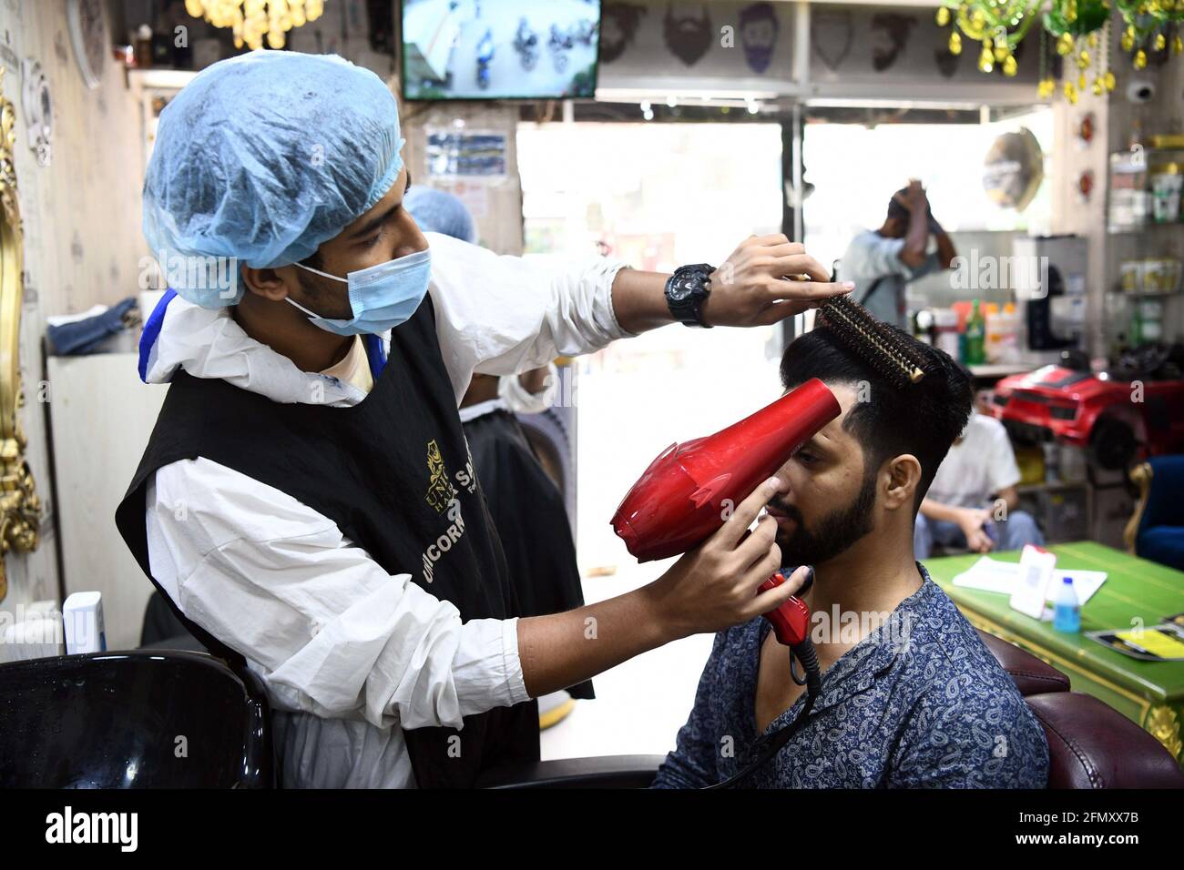 A salon staff wearing personal protective equipment (PPE) as a ...