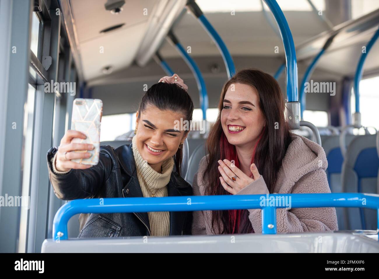 Two young women pulling faces and taking a selfie of themselves inside ...