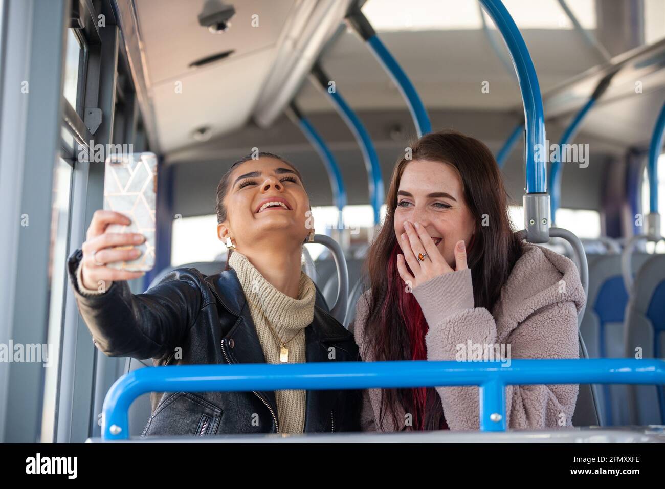 Two young women pulling faces and taking a selfie of themselves inside ...