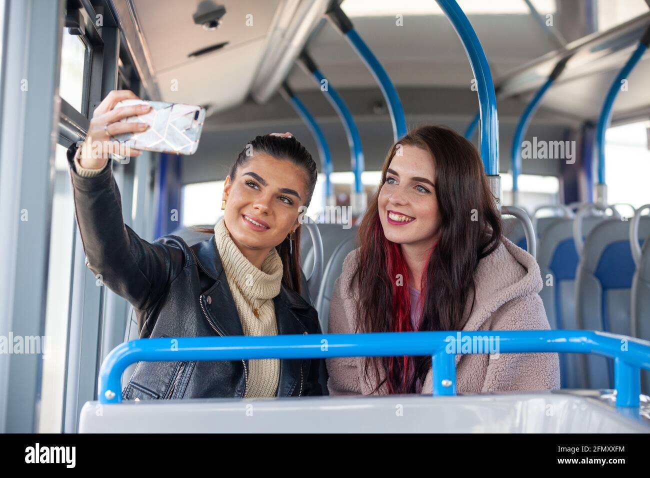 Two young women pulling faces and taking a selfie of themselves inside ...