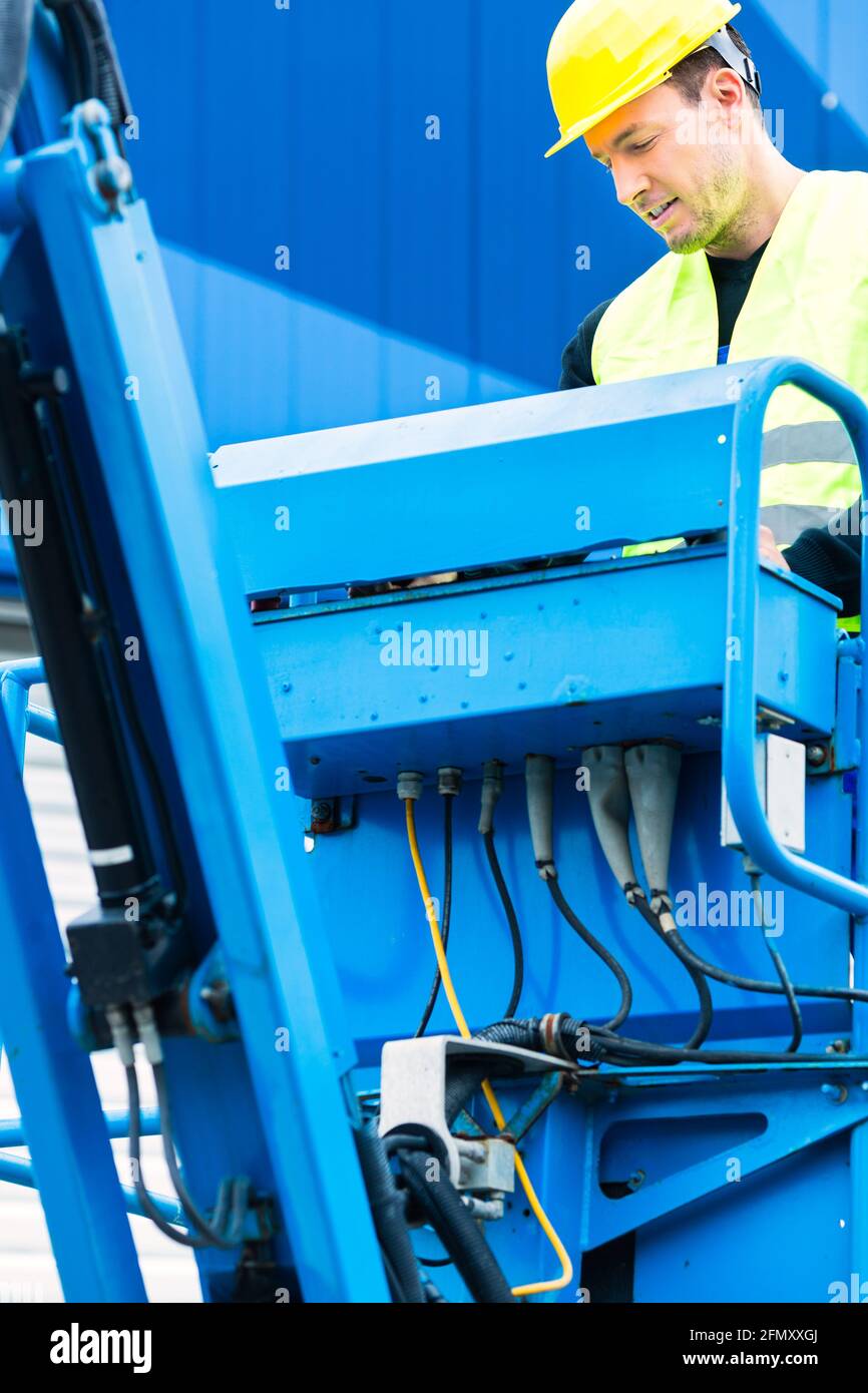 Construction workers or crane driver on site driving hydraulic lifting ...