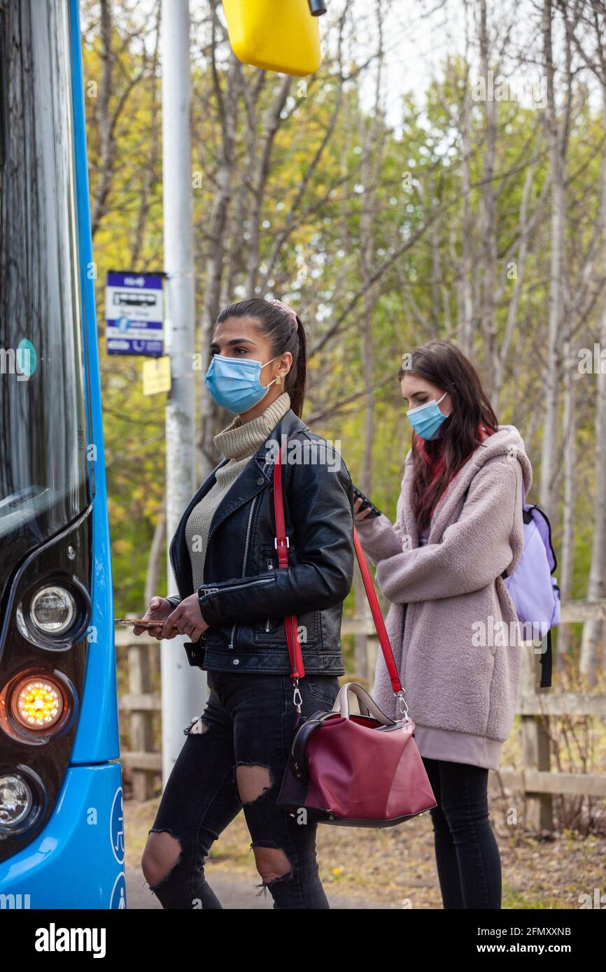 Two young women waiting at a bus stop in the street Stock Photo - Alamy