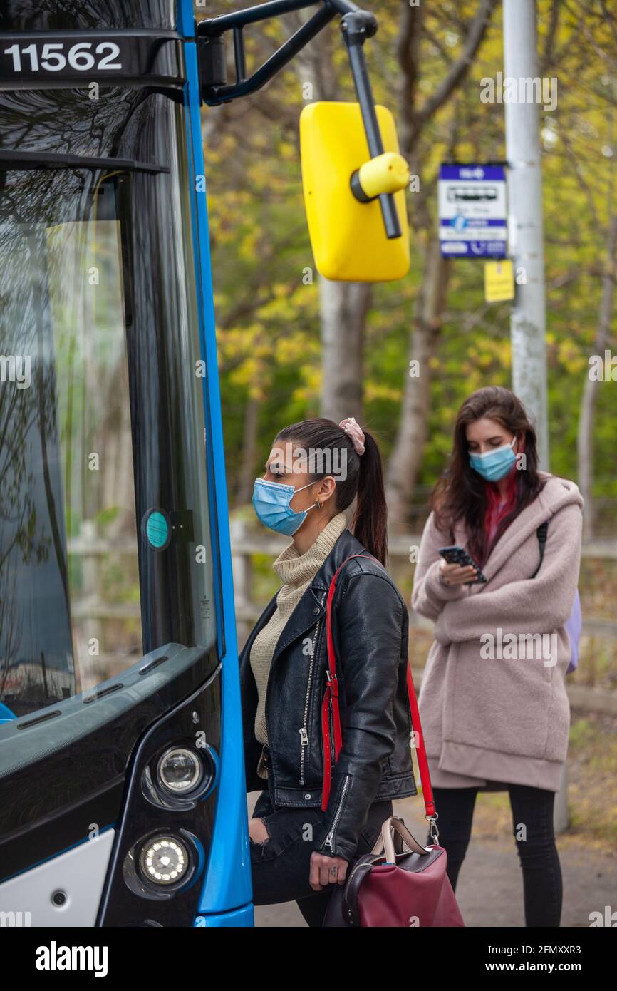 Two young women about to board a bus during the day Stock Photo - Alamy