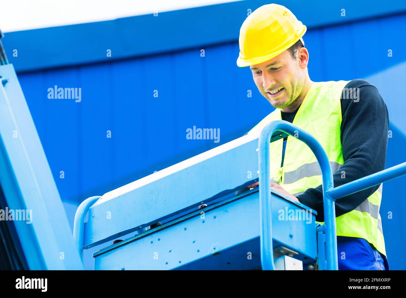 Construction workers or crane driver on site driving hydraulic lifting ...