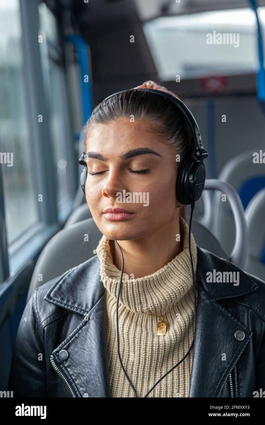 Young woman listening to music on bus with eyes closed Stock Photo - Alamy