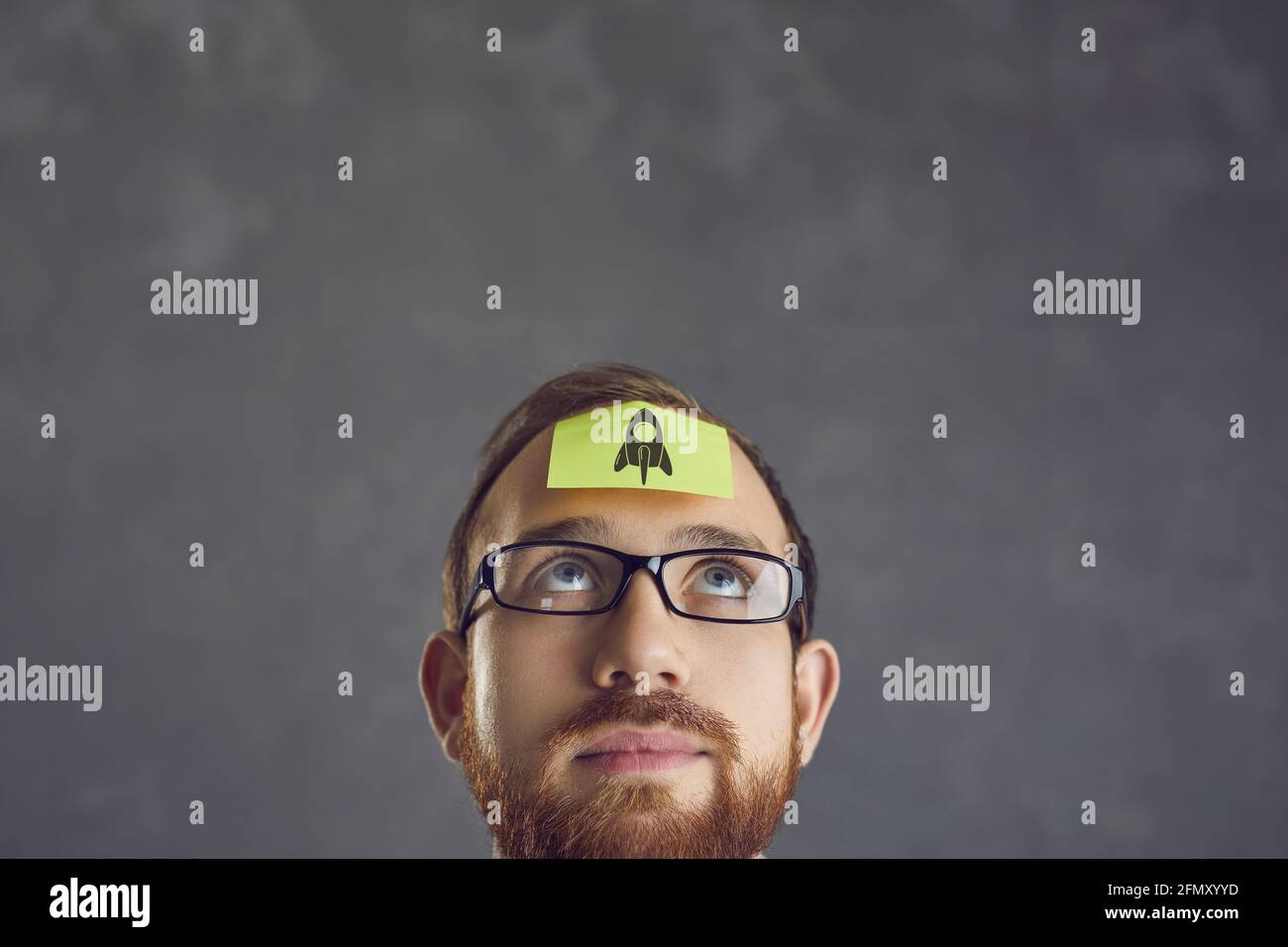 Businessman looking up at his forehead with post it note with picture ...