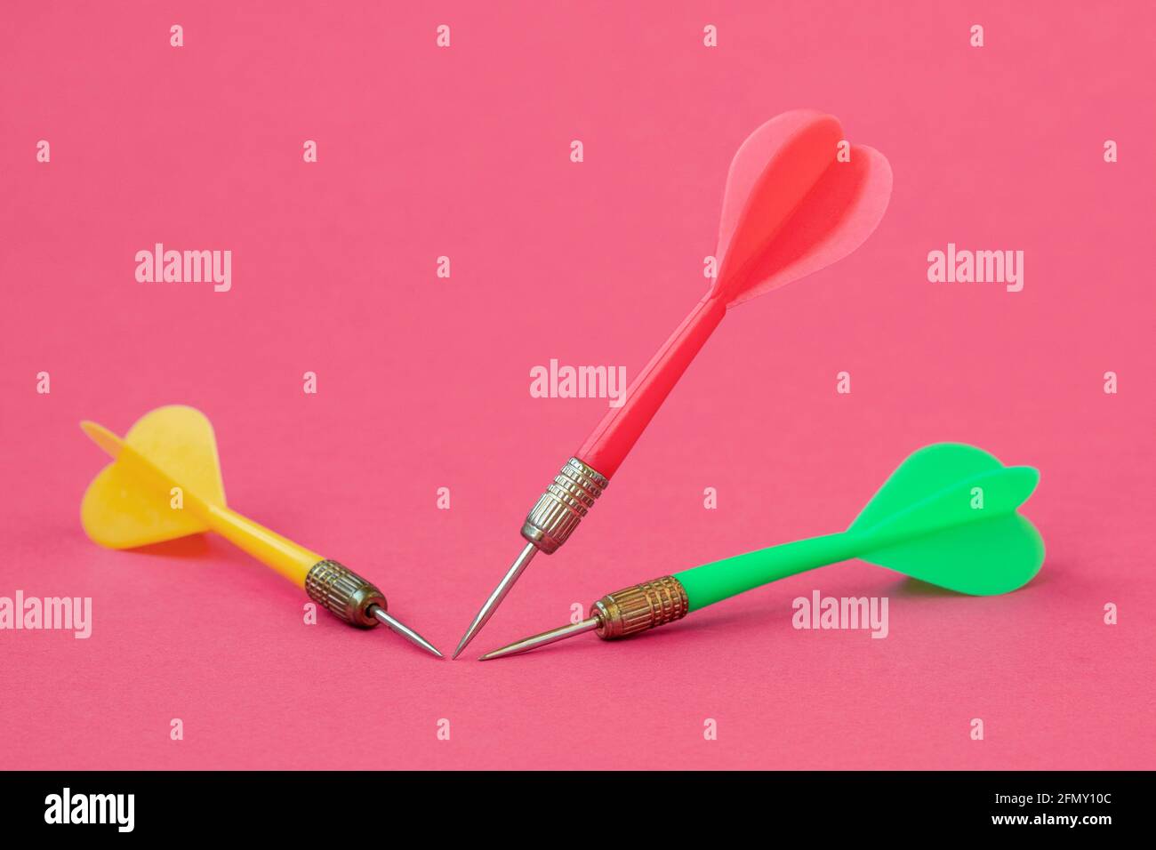 Three colored dart arrows on the pink background Stock Photo - Alamy