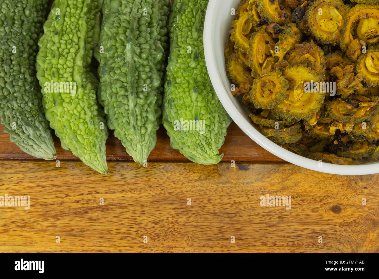 Cooked bitter gourd and raw bitter gourd kept alongside each other ...