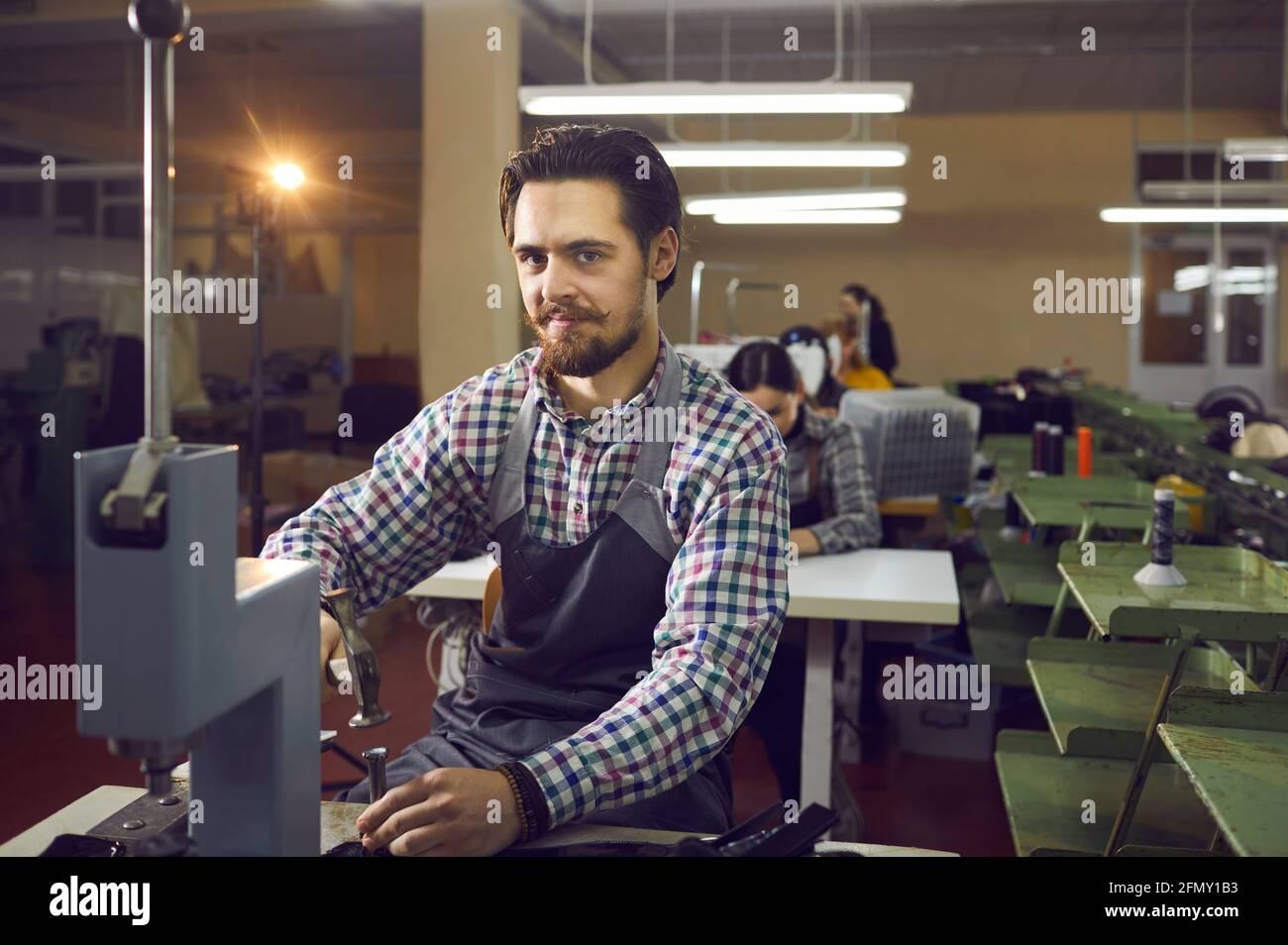 Shoe factory worker in manufacturing workshop using special footwear ...