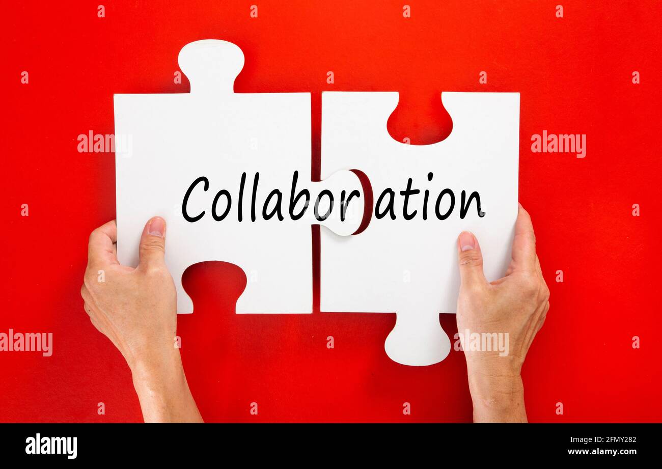 Two hands connect puzzles on a red background. Cooperation and teamwork ...
