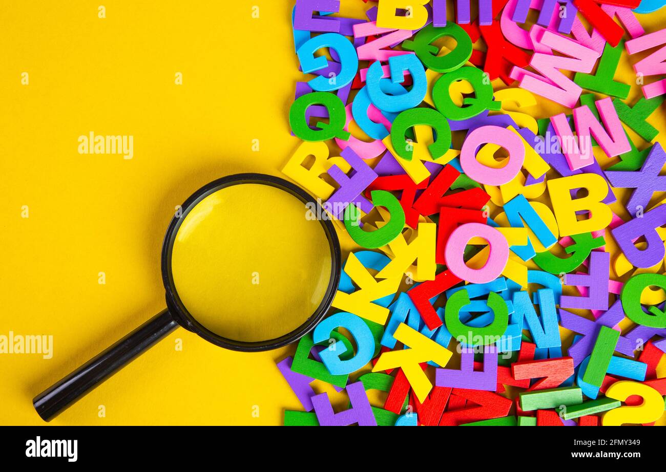 Magnifying glass with colorful alphabet on yellow background.Education ...