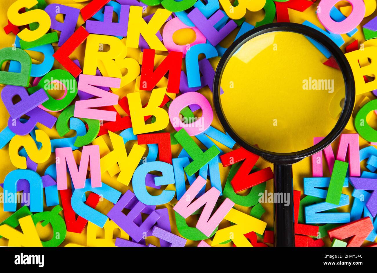 Magnifying glass with colorful alphabet on yellow background.Education ...