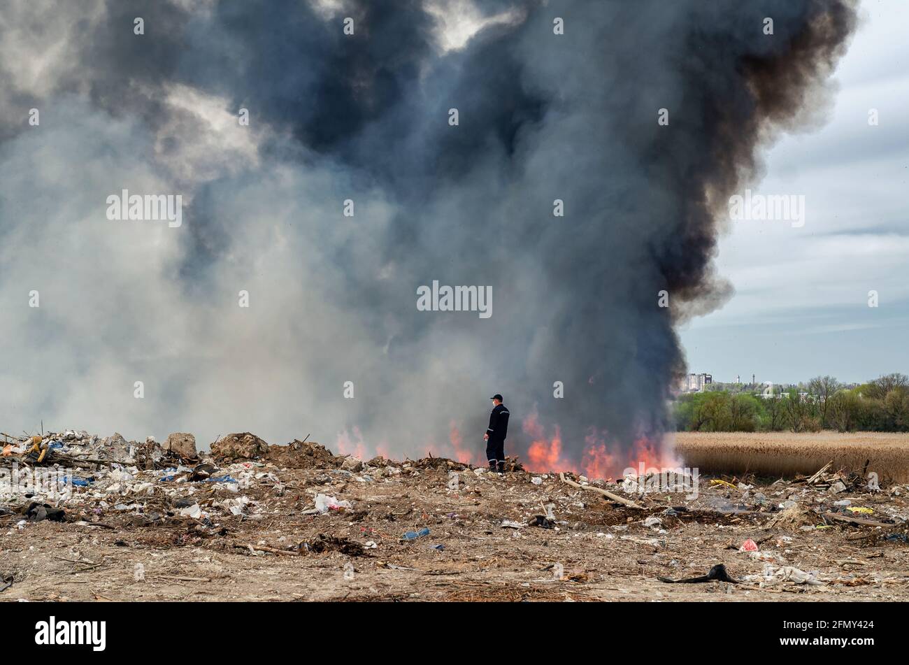 firefighter looks at large fire and smoke from dry grass Stock Photo ...