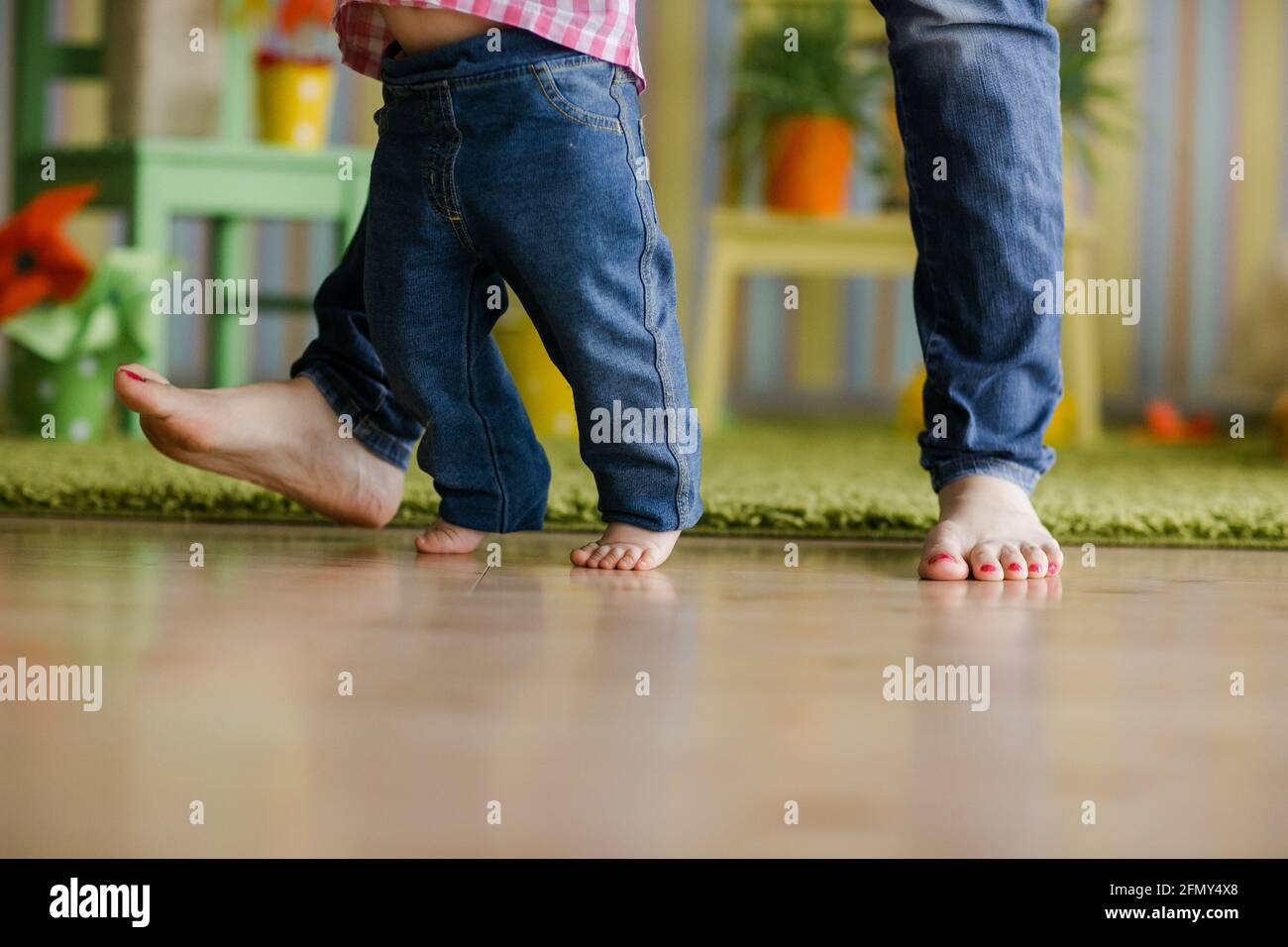 Baby taking first steps with mother's help at home. happy family ...