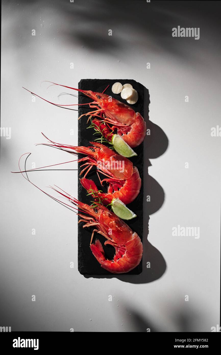 Three red prawns with condiments on grey background with shadow Stock ...