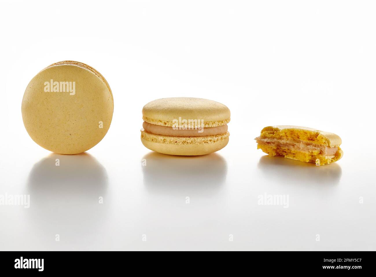 Two whole and one bitten macarons on white surface Stock Photo - Alamy