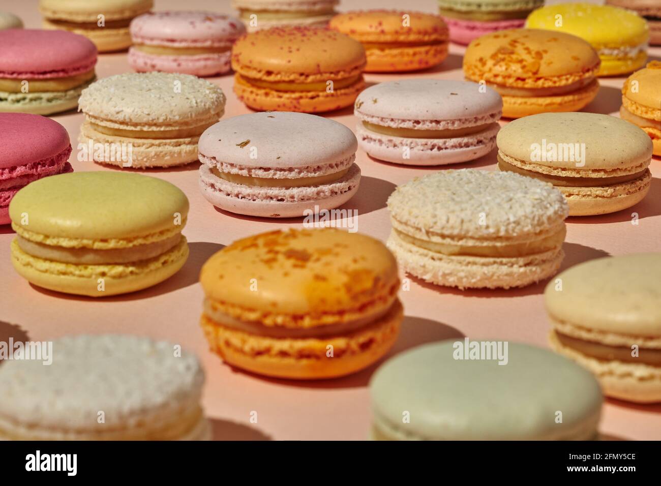 Colorful French macarons on light pink surface Stock Photo - Alamy