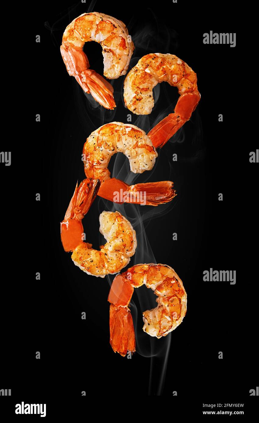 Grilled shrimp tails hovering in white haze on black background Stock ...