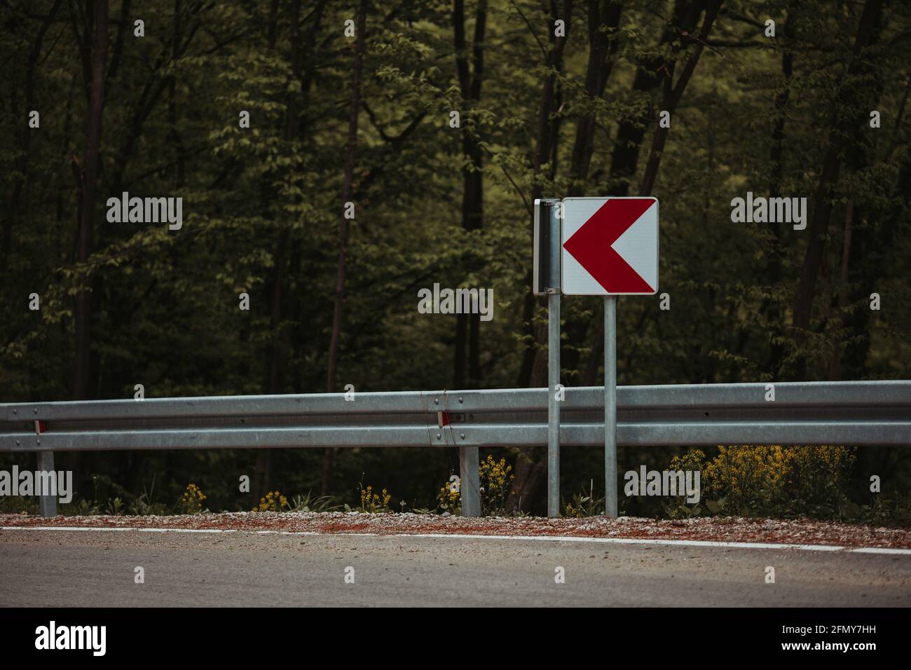 Red arrow sign on a road through a forest Stock Photo - Alamy