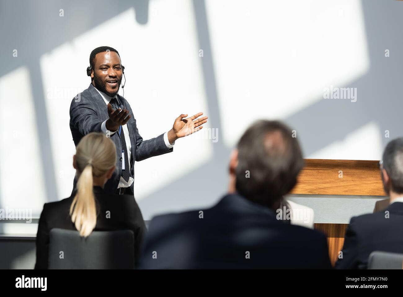 pleased african american lecturer pointing with hand during seminar ...