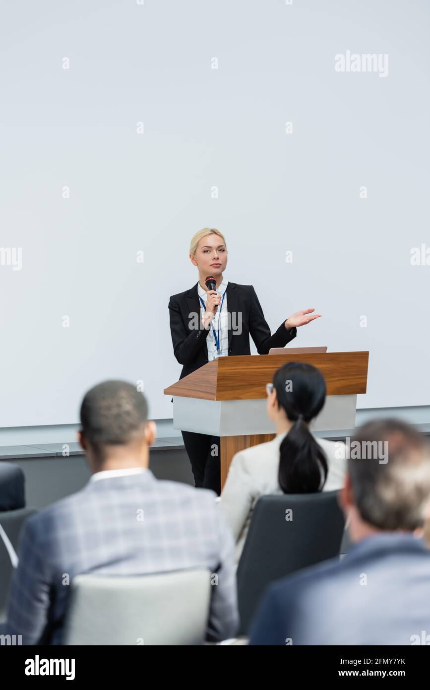 back view of audience near lecturer pointing with hand while speaking ...