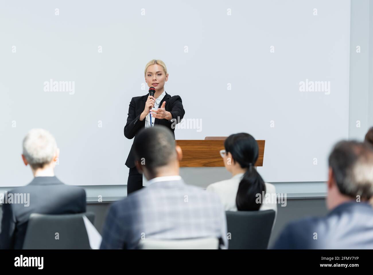 young lecturer talking in microphone while pointing with finger at ...