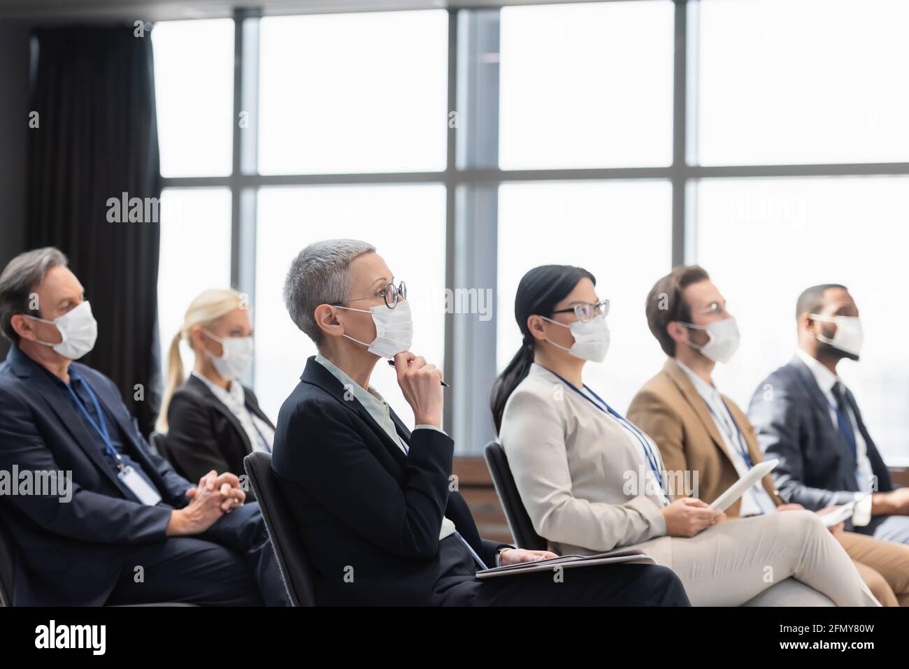 multiethnic business people in medical masks sitting in conference room ...