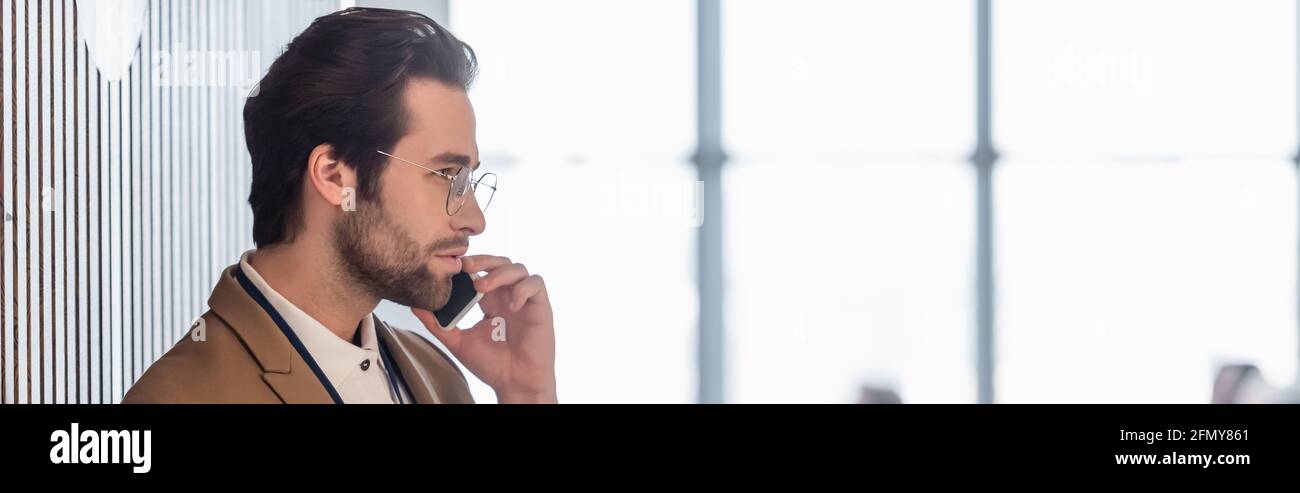Side view of businessman in eyeglasses talking on cellphone, banner ...