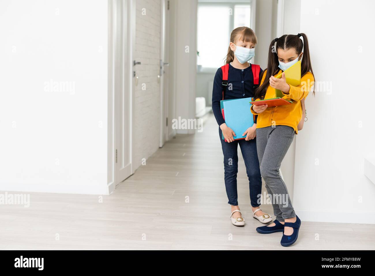 Cute little girls of primary hug each other with the mask on. School ...