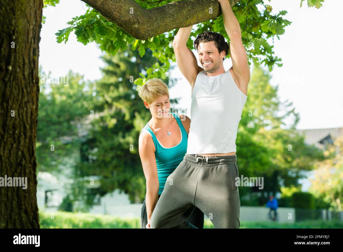 Young woman and personal trainer exercising chins or pull ups in City ...