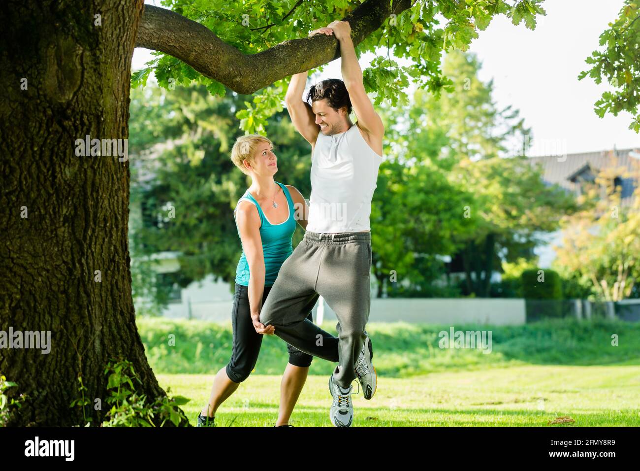 Young woman and personal trainer exercising chins or pull ups in City ...