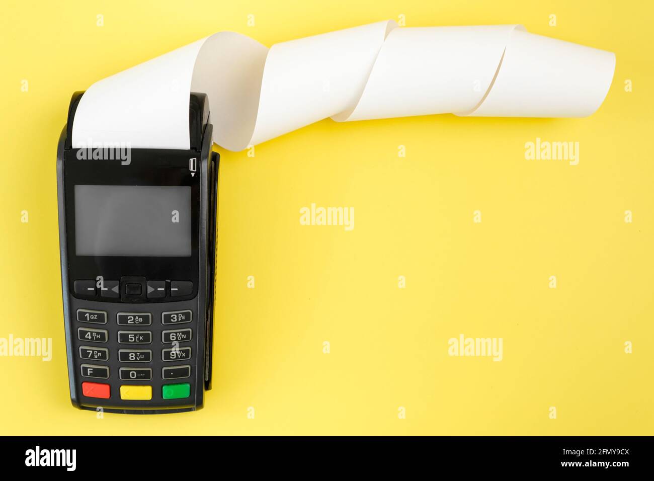Payment terminal POS with a roll cash tape on the yellow background ...