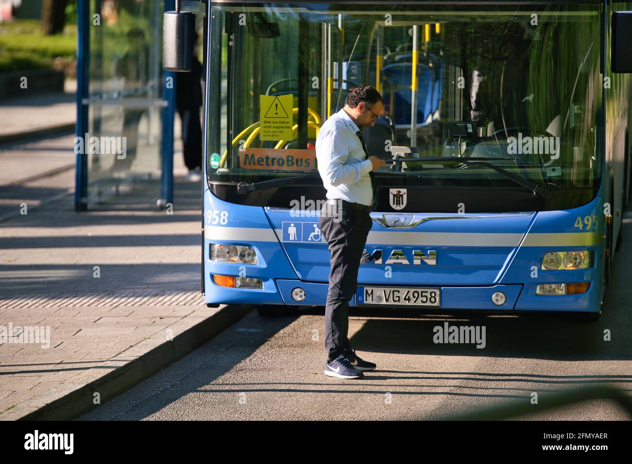 MUNICH, GERMANY - May 11, 2021: Bus driver checks his smartphone during ...