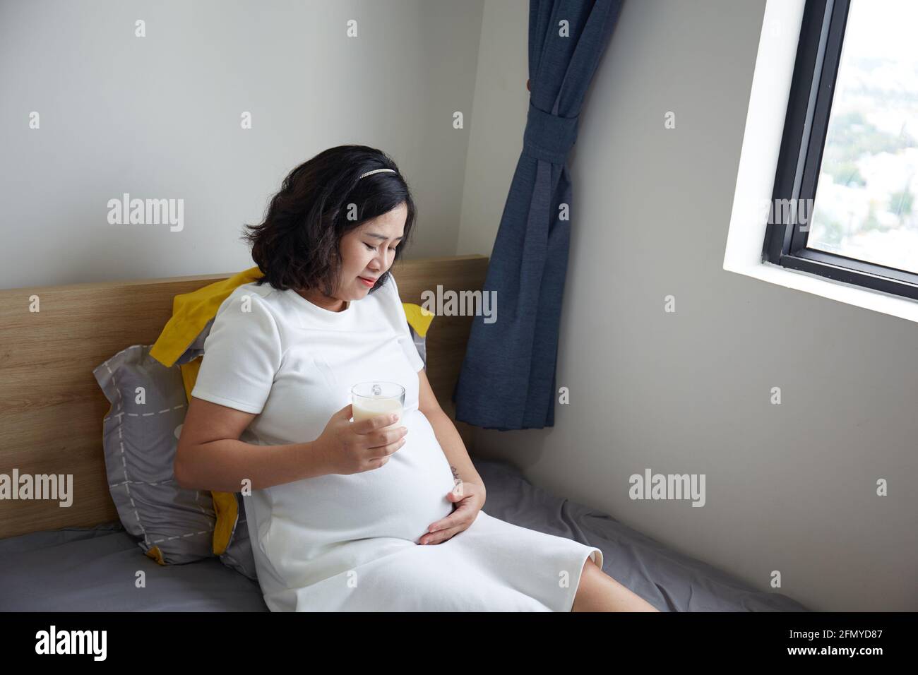 Closeup shot of a Southeast Asian pregnant female on a couch indoors ...