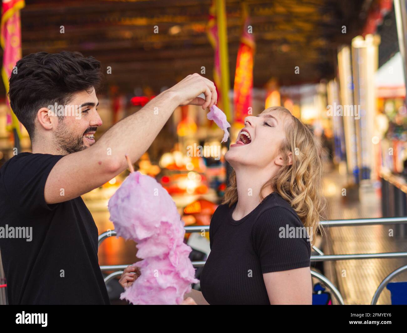 Couple eating candy cotton together in the amusement park Stock Photo ...