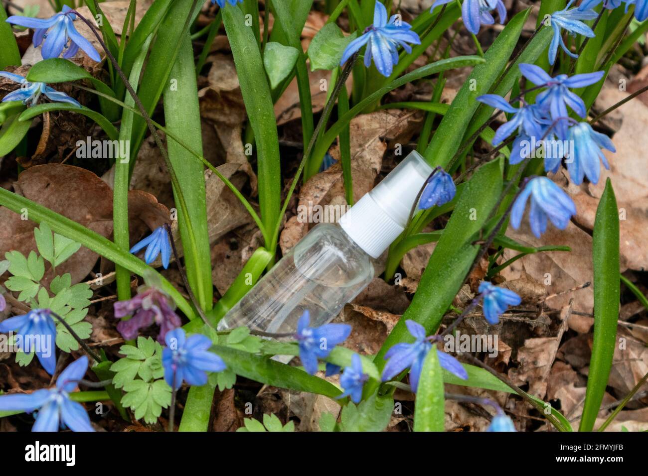 Clear liquid spray pump bottle in blooming pretty flower lawn of blue ...