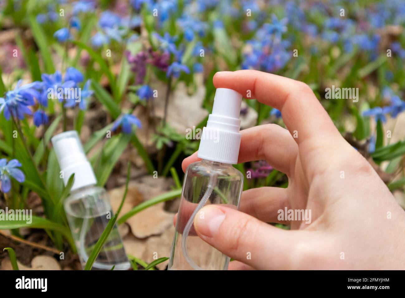 Hand spray clear liquid pump bottle in blooming spring flower lawn of ...