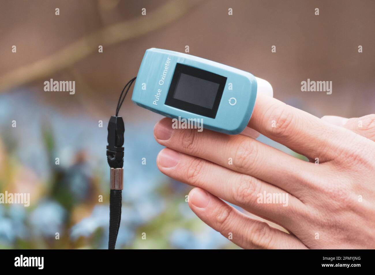 Pulse oximeter on a hands finger. Light blue oxygen saturation meter ...