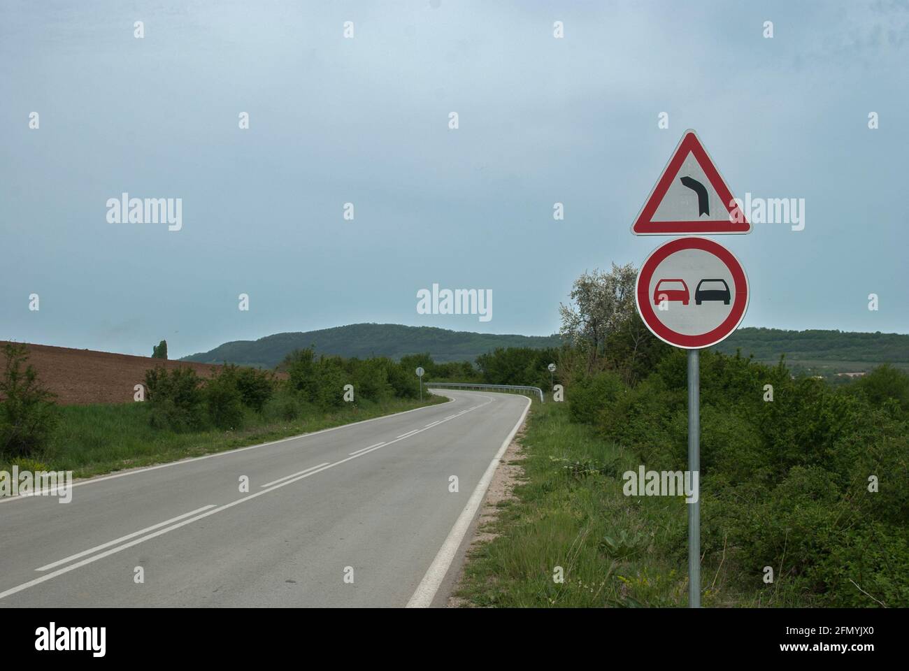 Country road bend with road curve attention traffic sign and overtaking ...