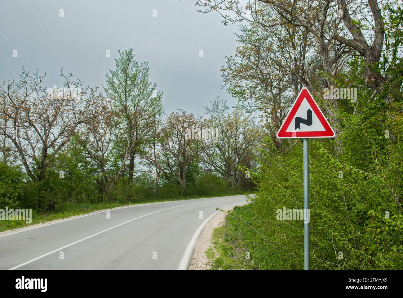 Country road bend and road curve attention traffic sign Stock Photo - Alamy