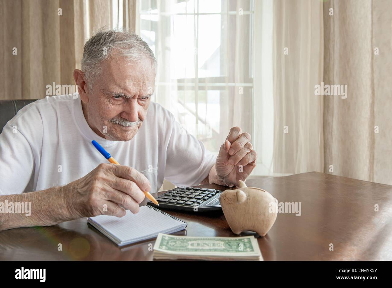 Old Man With A Pencil Counts Pennies From The Pension Fund Sitting At A