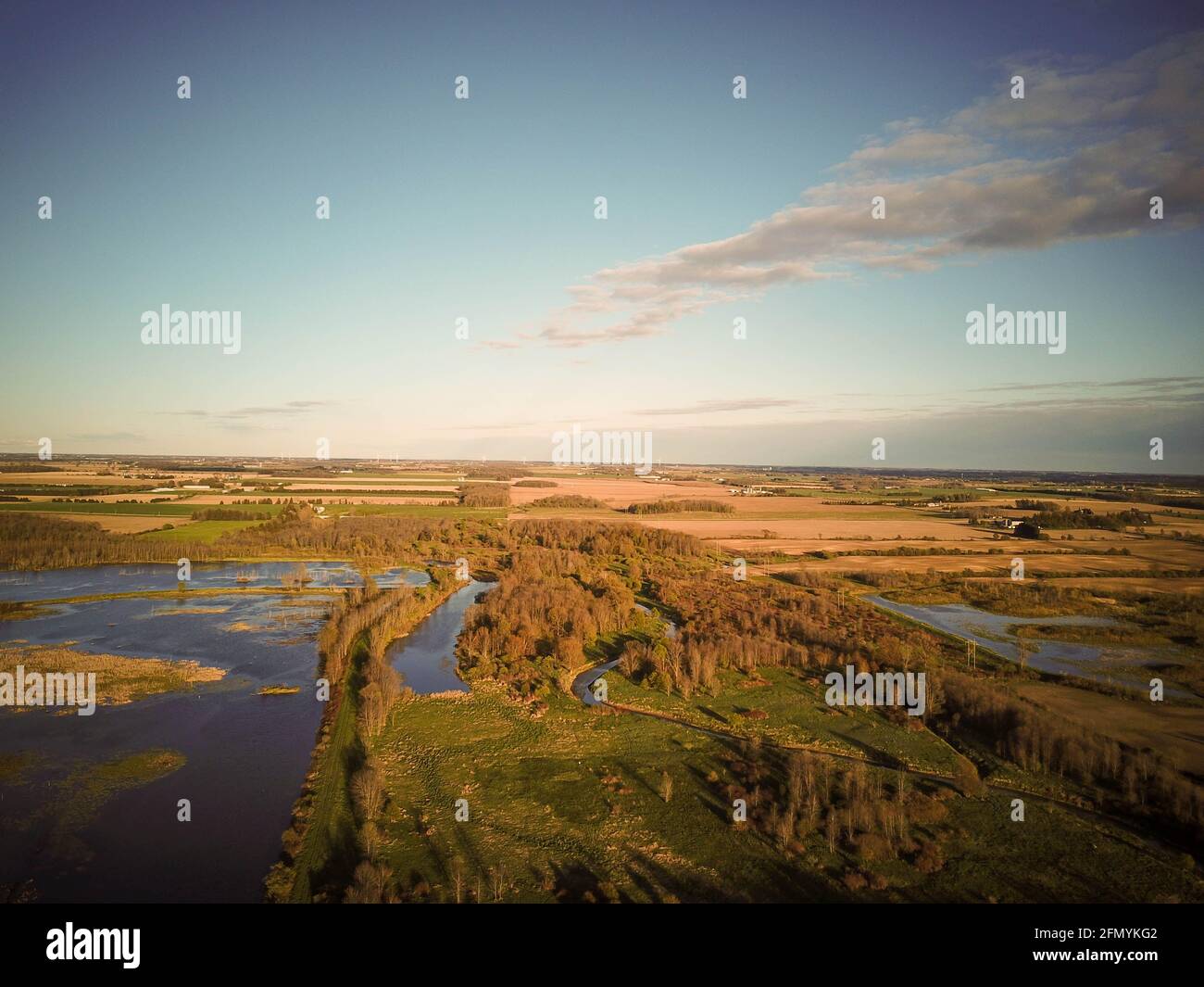 Aerial view of small river flowing through green marshy riparian ...