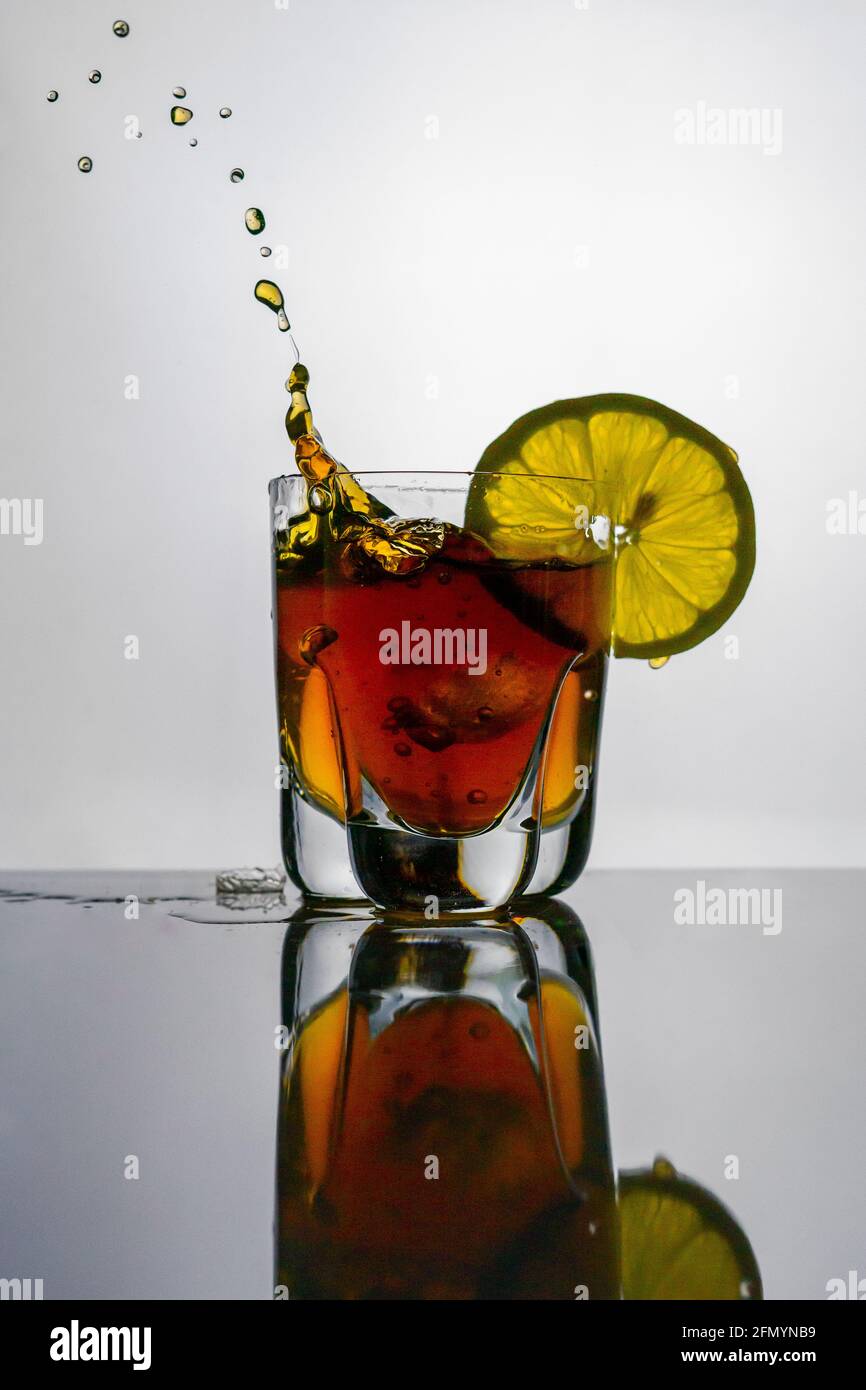 ice cube dropped into iced tea with lemon spilled tea Stock Photo - Alamy